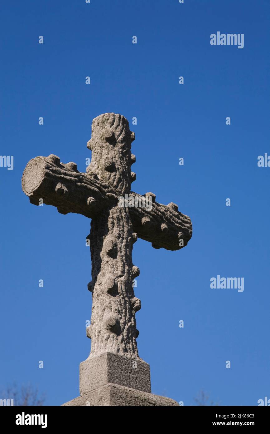 Close-up of a cement log shaped cross atop a headstone in cemetery ...