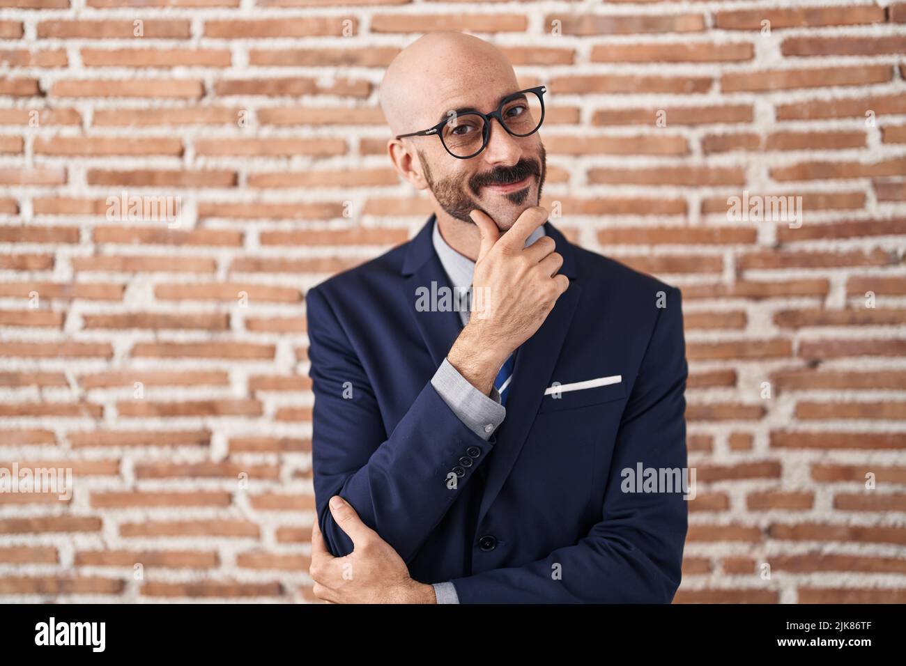 Bald man with beard wearing business clothes and glasses looking ...