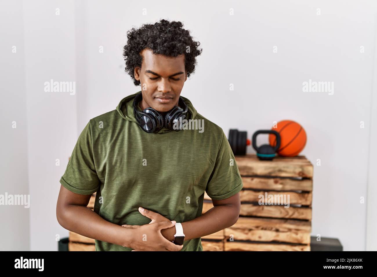 African man with curly hair wearing sportswear at the gym with hand on ...