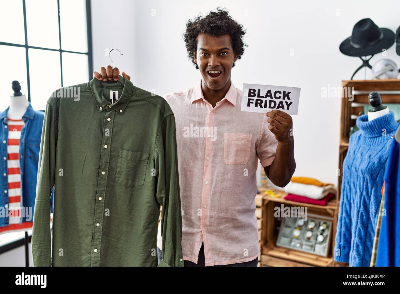 African man with curly hair holding black friday banner at retail shop ...