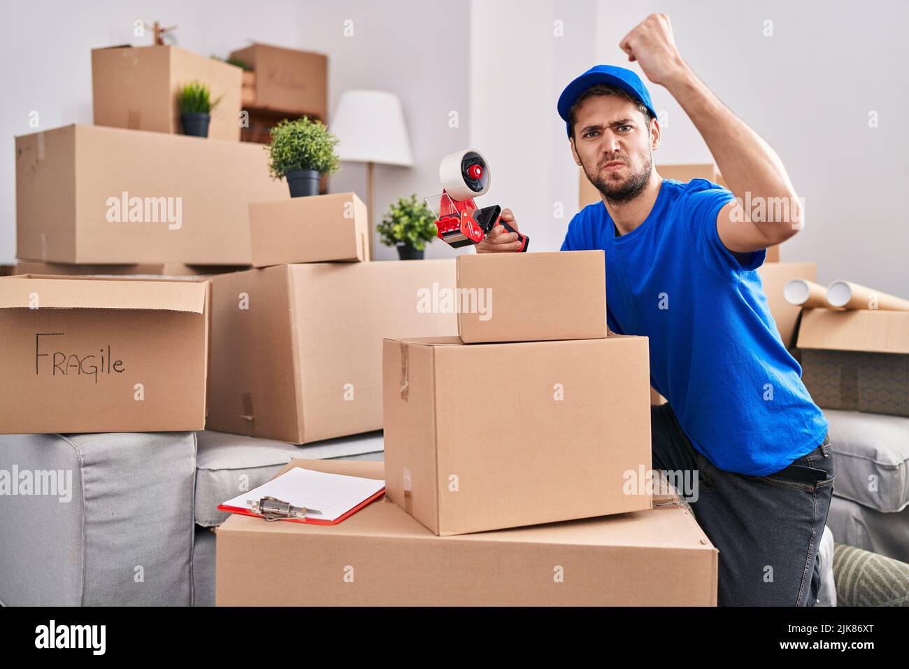 Hispanic man with beard working moving boxes annoyed and frustrated ...