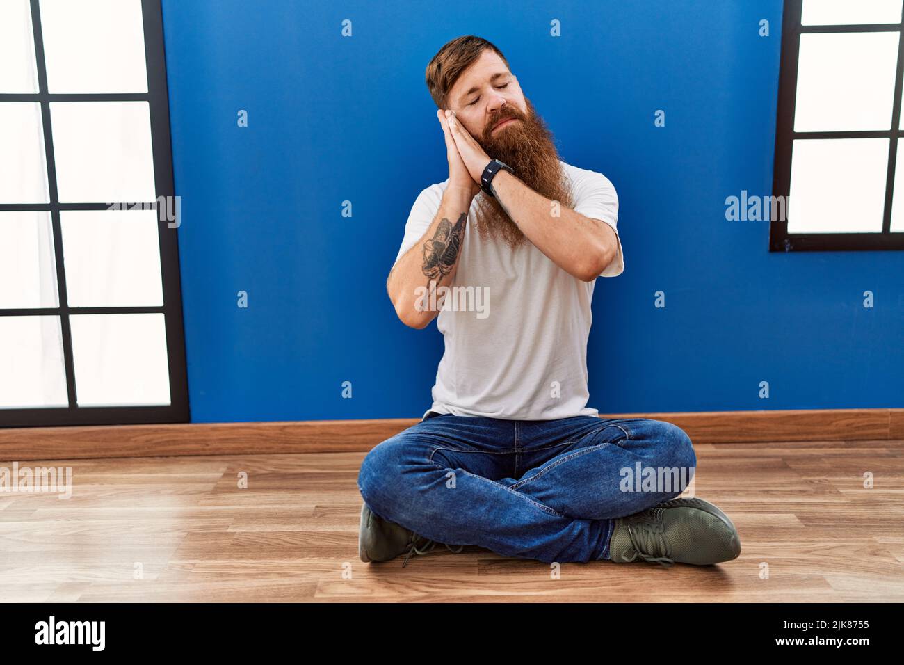 Redhead Man With Long Beard Sitting On The Floor At Empty Room Sleeping