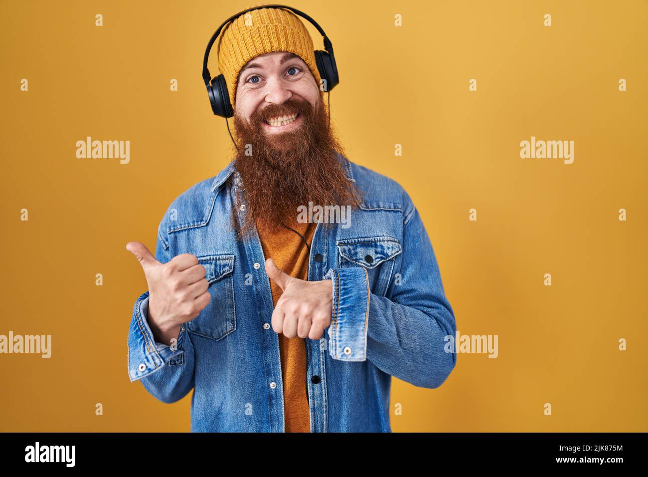 Caucasian man with long beard listening to music using headphones ...