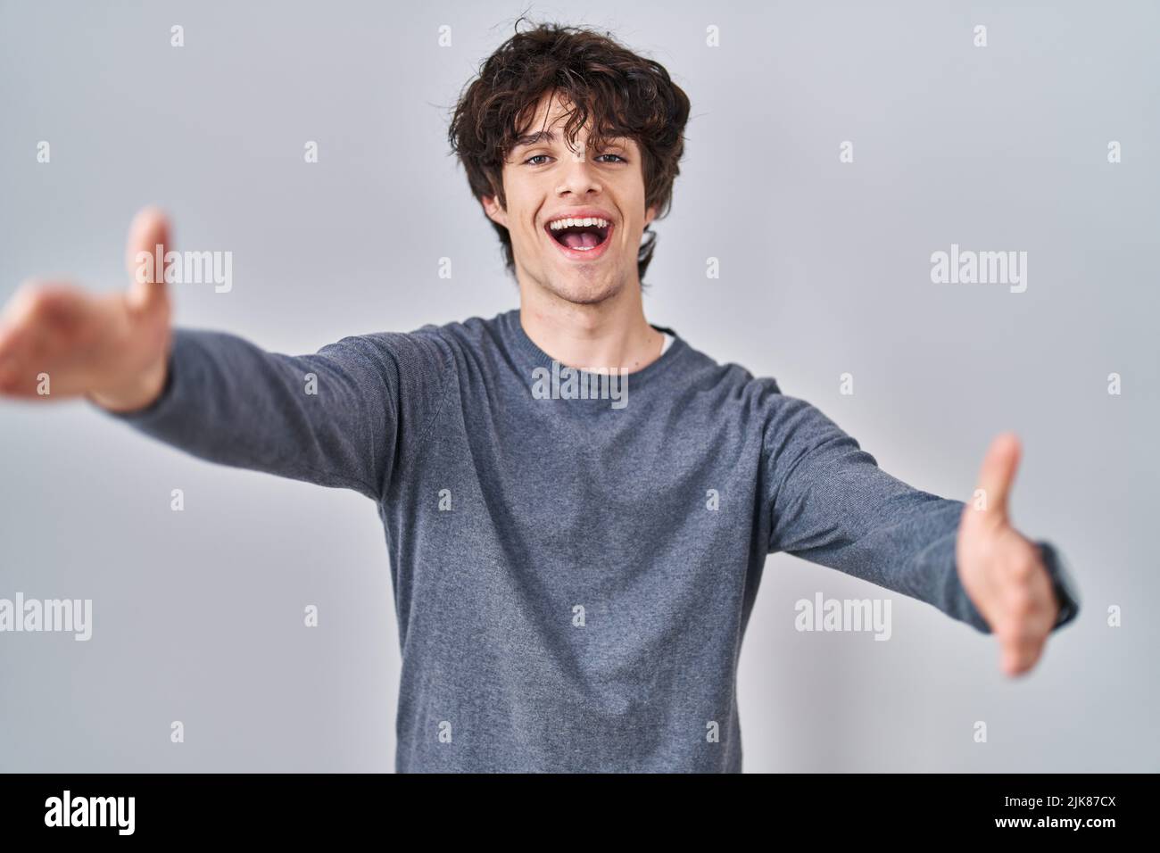 Young man standing over isolated background looking at the camera ...