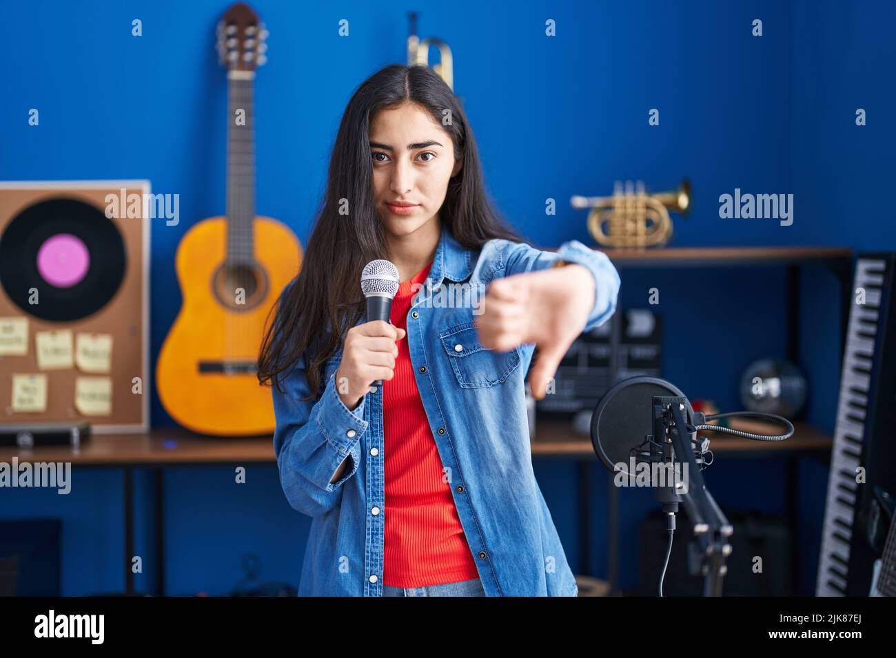 Young teenager girl singing song using microphone with angry face ...