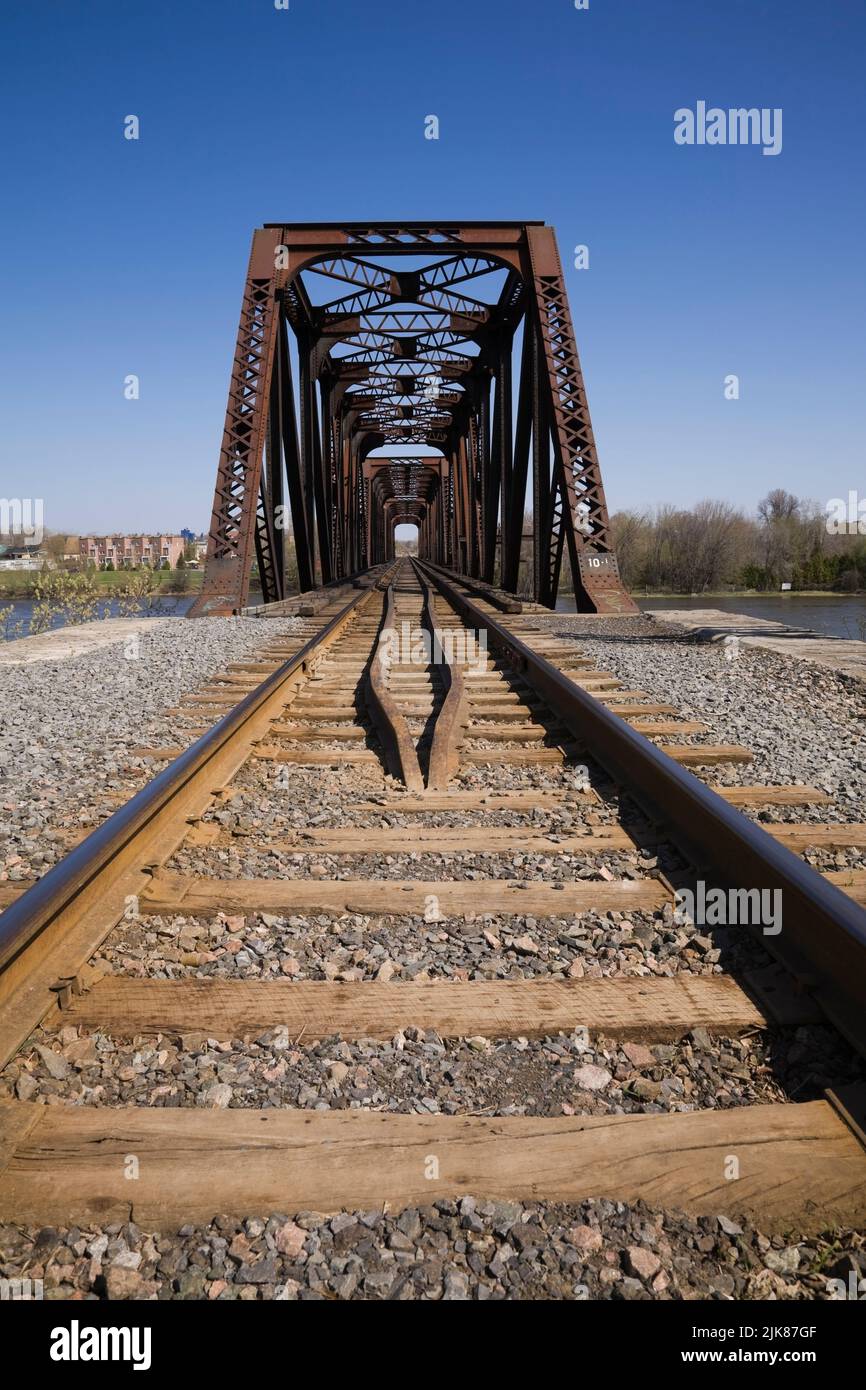 Close-up of railroad tracks leading to rusted steel railroad bridge ...