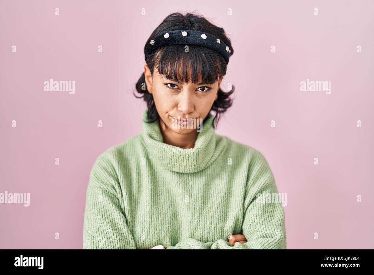 Young beautiful woman standing over pink background skeptic and nervous ...
