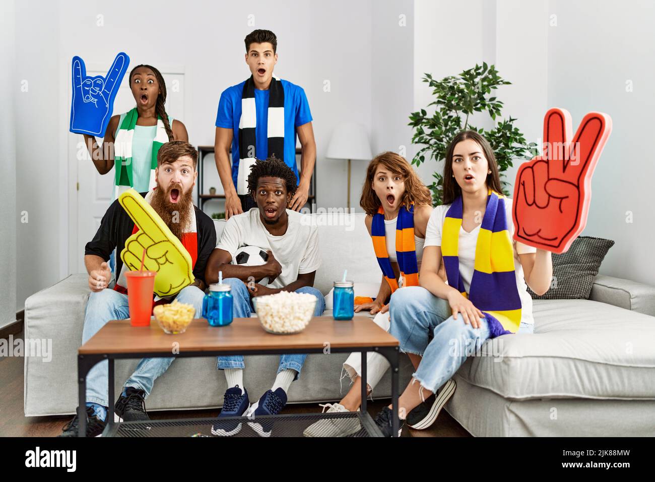 Group of friends supporting football team watching tv al home sitting ...