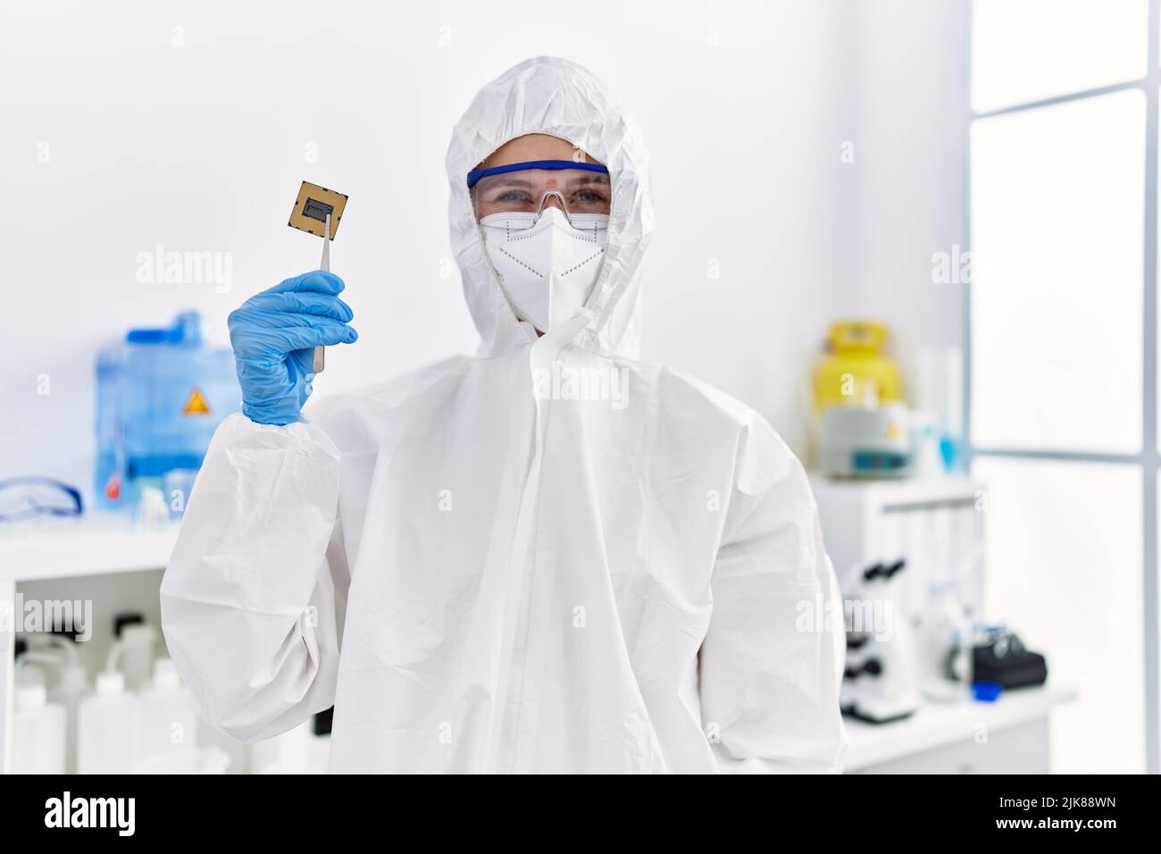 Young blonde woman holding cpu computer processor at laboratory looking ...