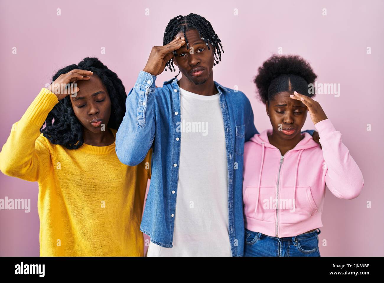 Group of three young black people standing together over pink ...