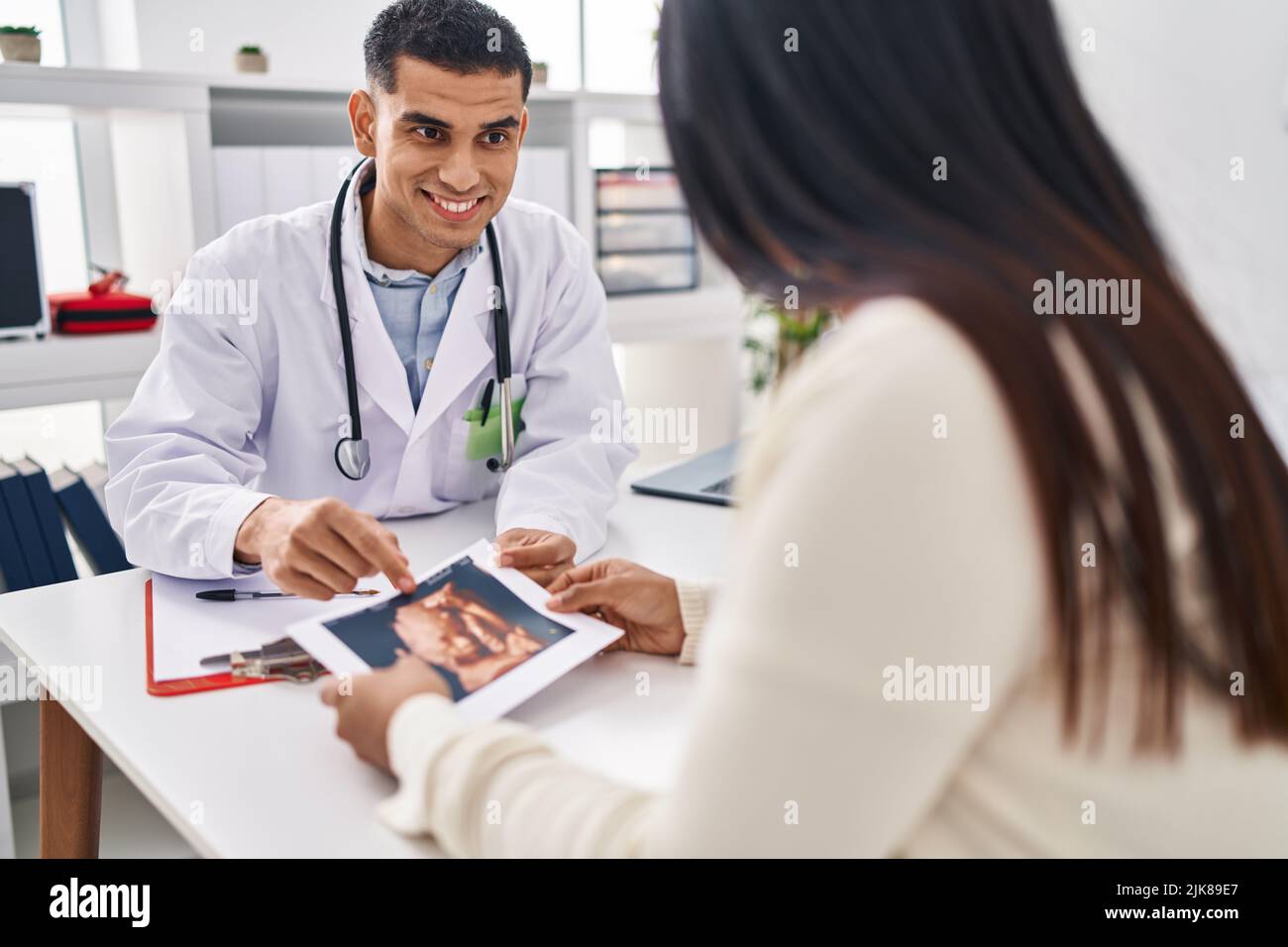 Young latin couple doctor and patient looking baby ecography at clinic ...