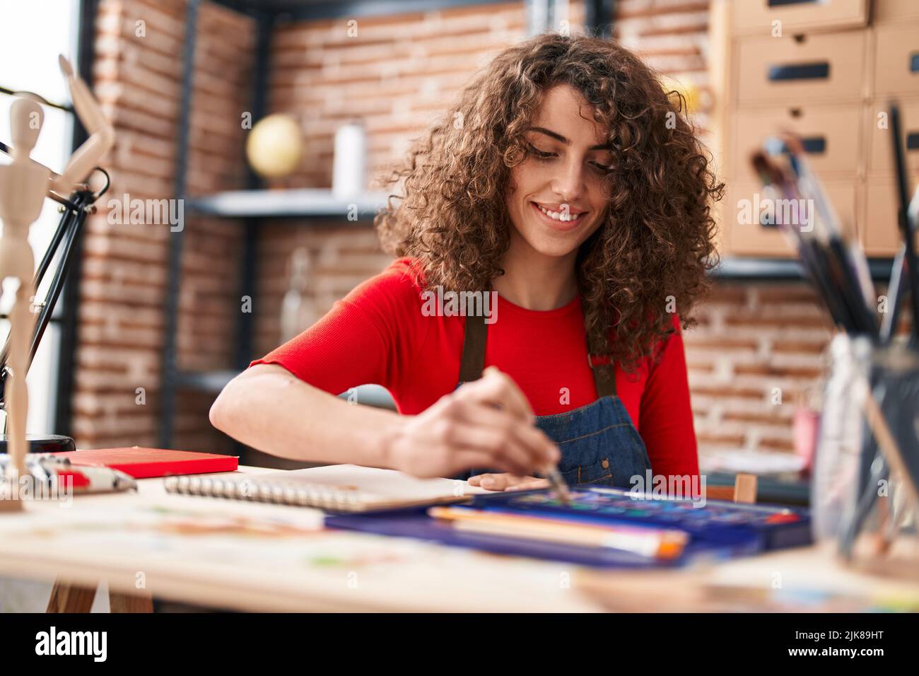 Young hispanic woman artist smiling confident drawing on notebook at ...