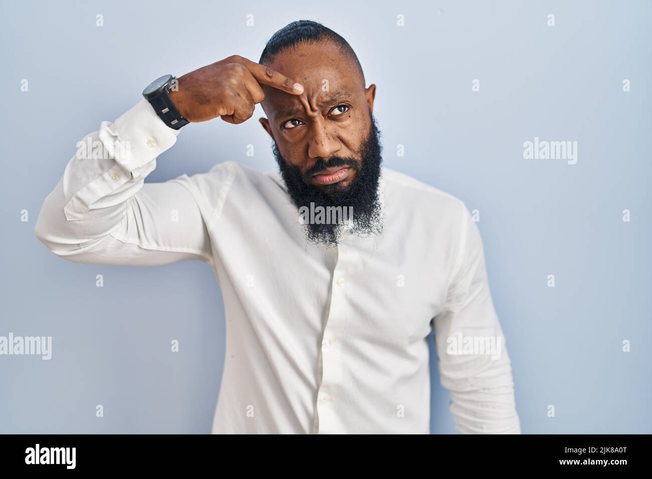 African american man standing over blue background pointing unhappy to ...