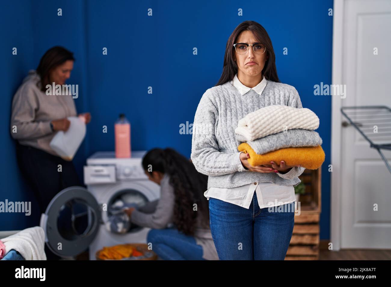 Three women doing laundry at home depressed and worry for distress ...
