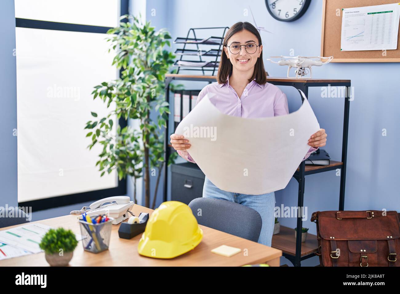 Young hispanic woman architect reading blueprints at office Stock Photo ...