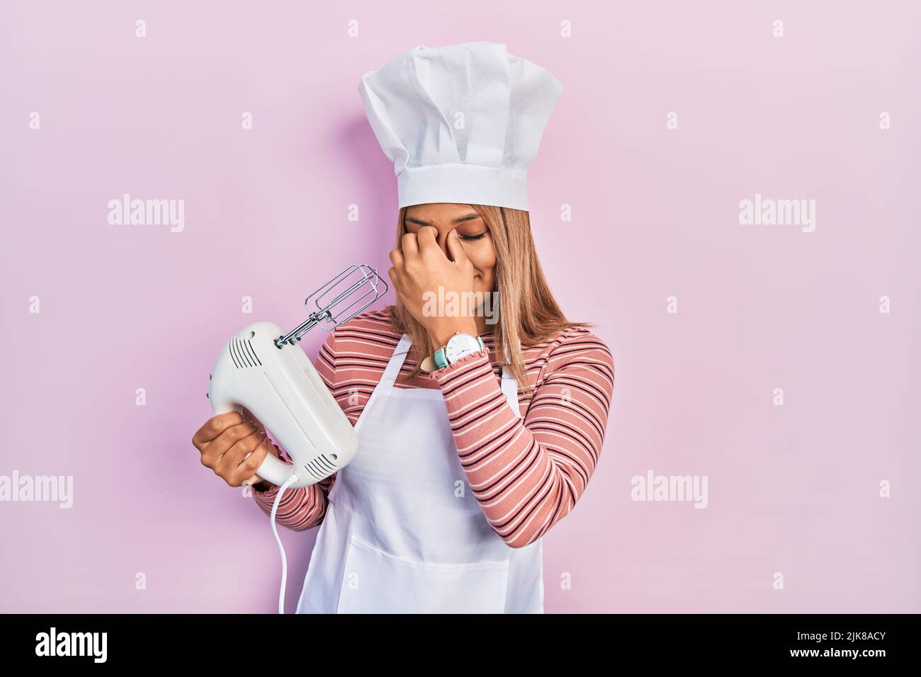 Beautiful hispanic woman holding pastry blender electric mixer tired ...