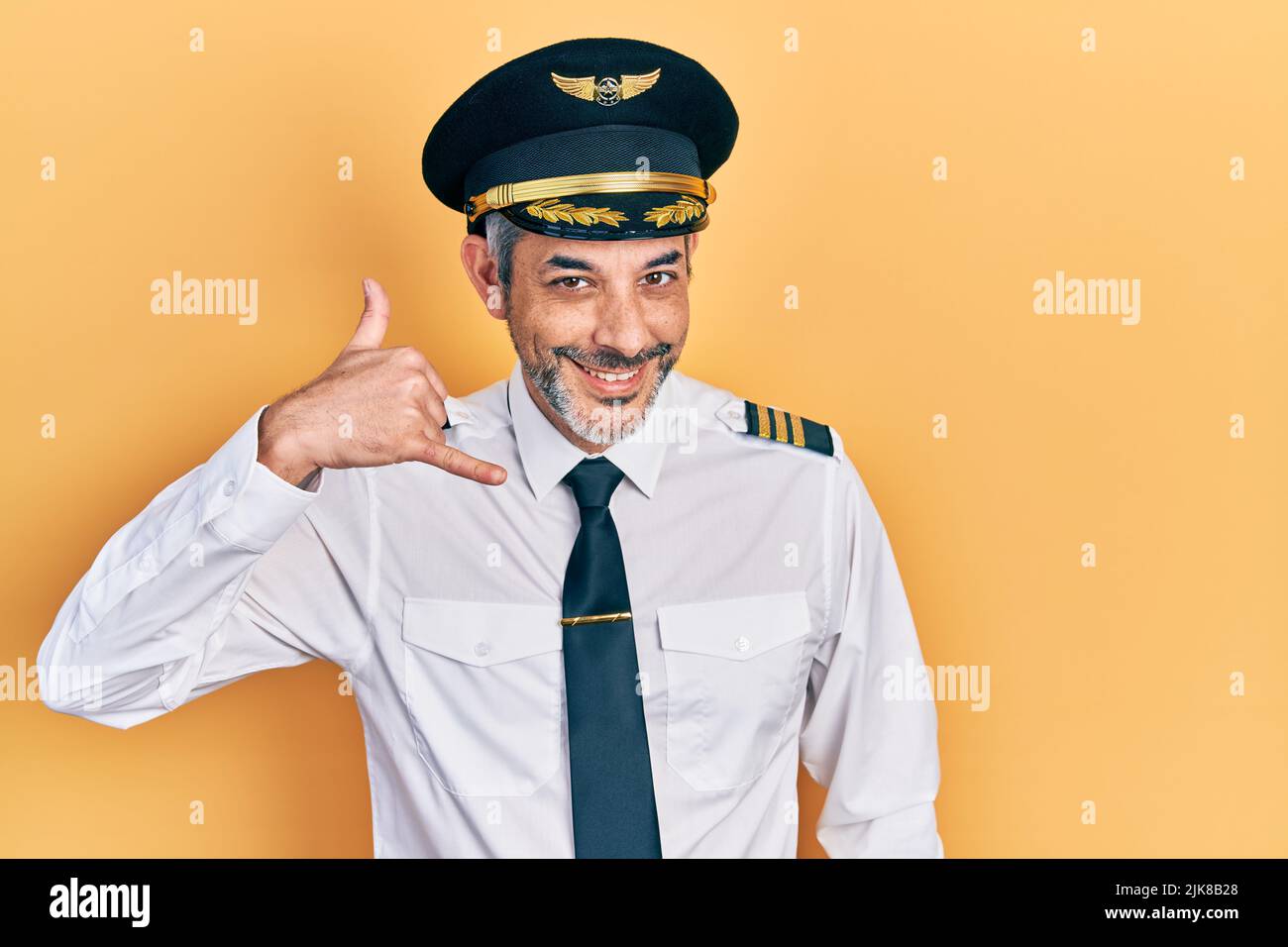 Handsome middle age man with grey hair wearing airplane pilot uniform ...