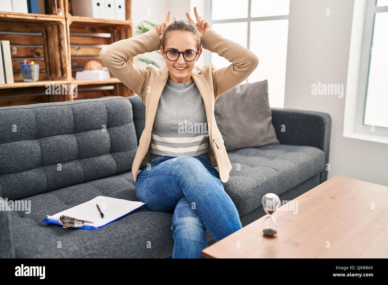 Young woman working at consultation office posing funny and crazy with ...