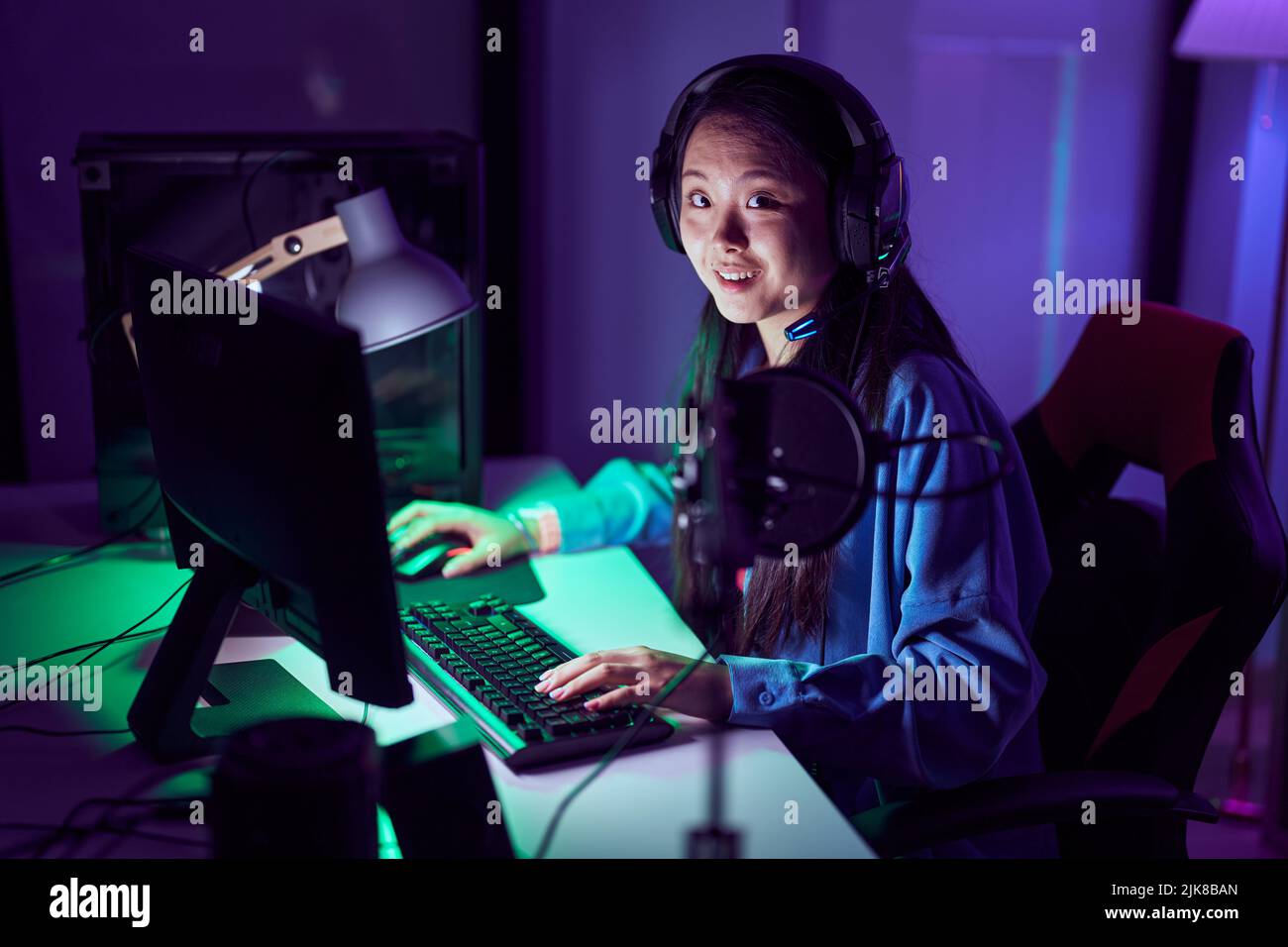Young chinese woman streamer playing video game using computer at ...