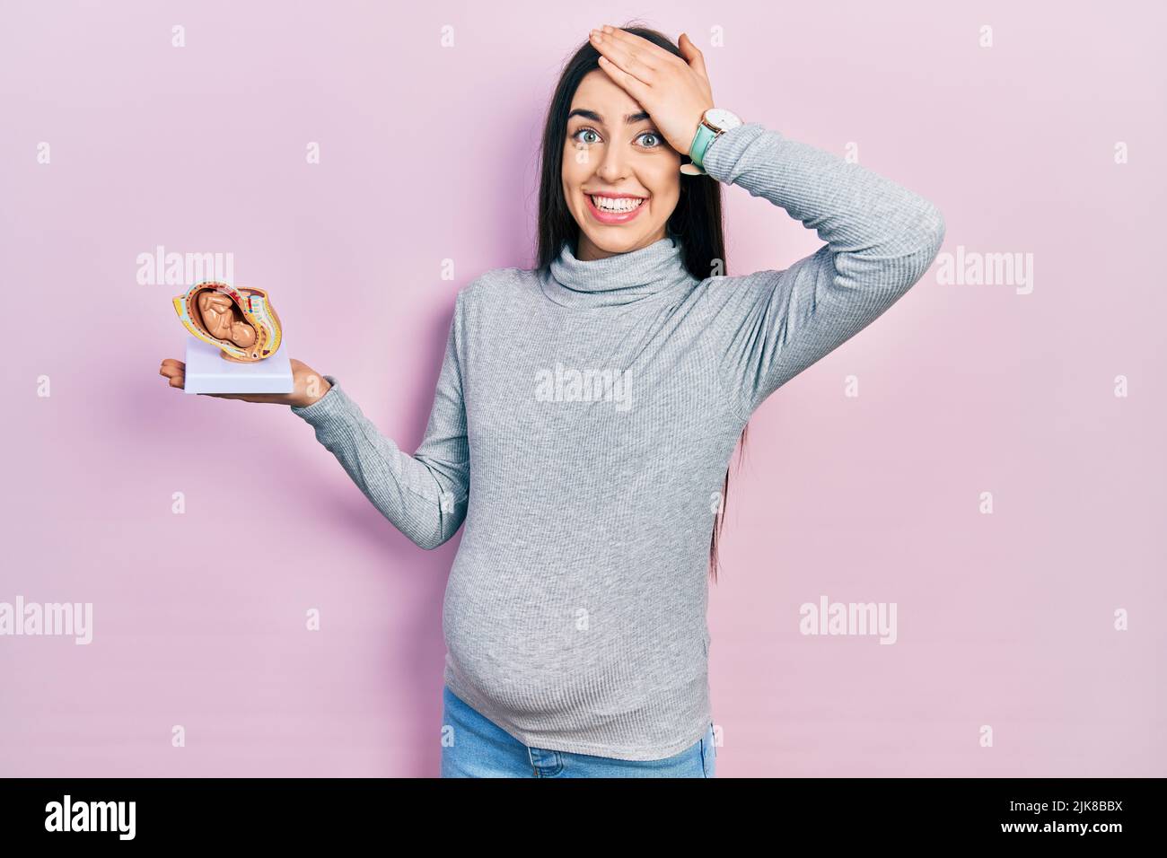 Beautiful woman with blue eyes expecting a baby, holding anatomic fetus ...