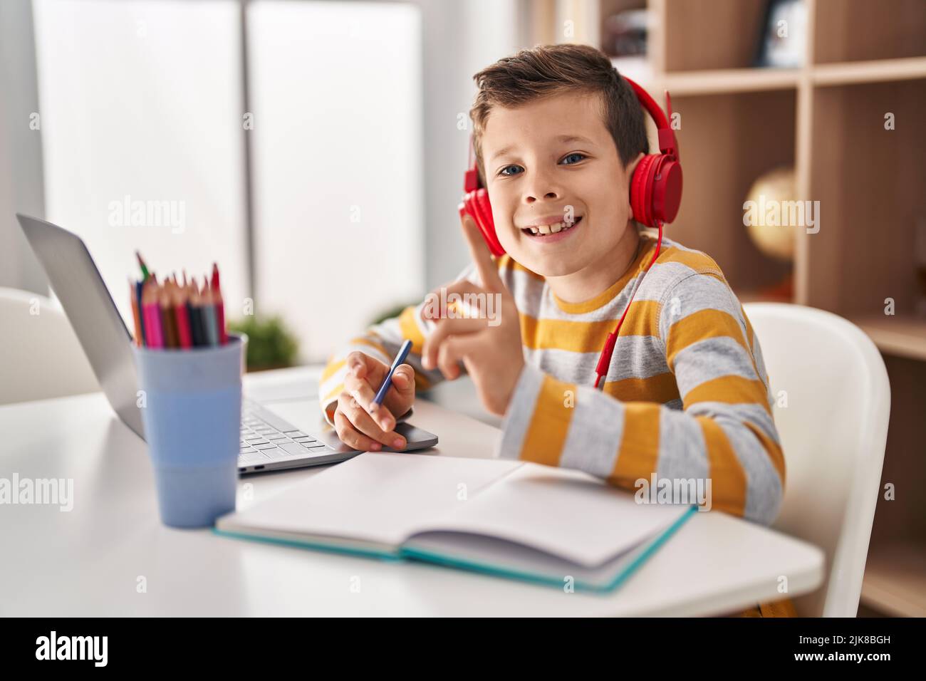 Young caucasian kid doing homework at home surprised with an idea or ...