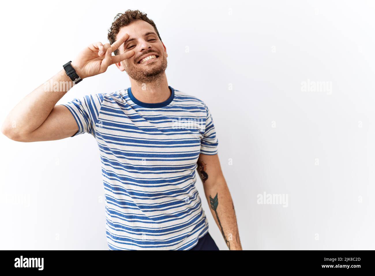Handsome young man standing over isolated background doing peace symbol ...