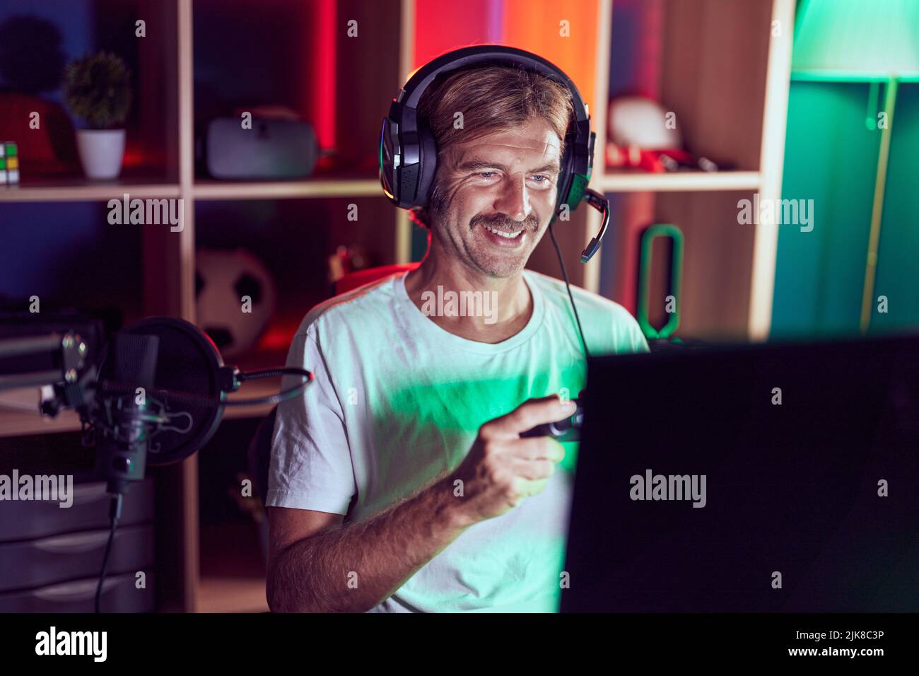 Young blond man streamer playing video game using joystick at gaming ...