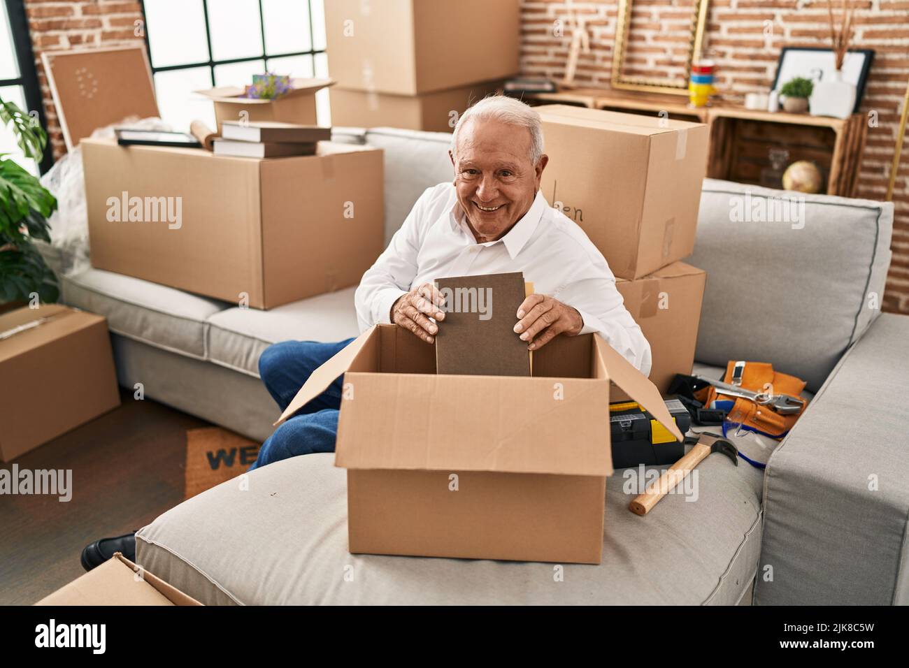 Senior man smiling confident unboxing package at new home Stock Photo ...