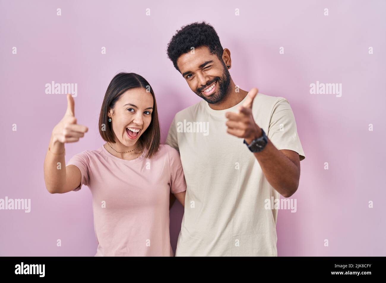 Young hispanic couple together over pink background pointing fingers to ...
