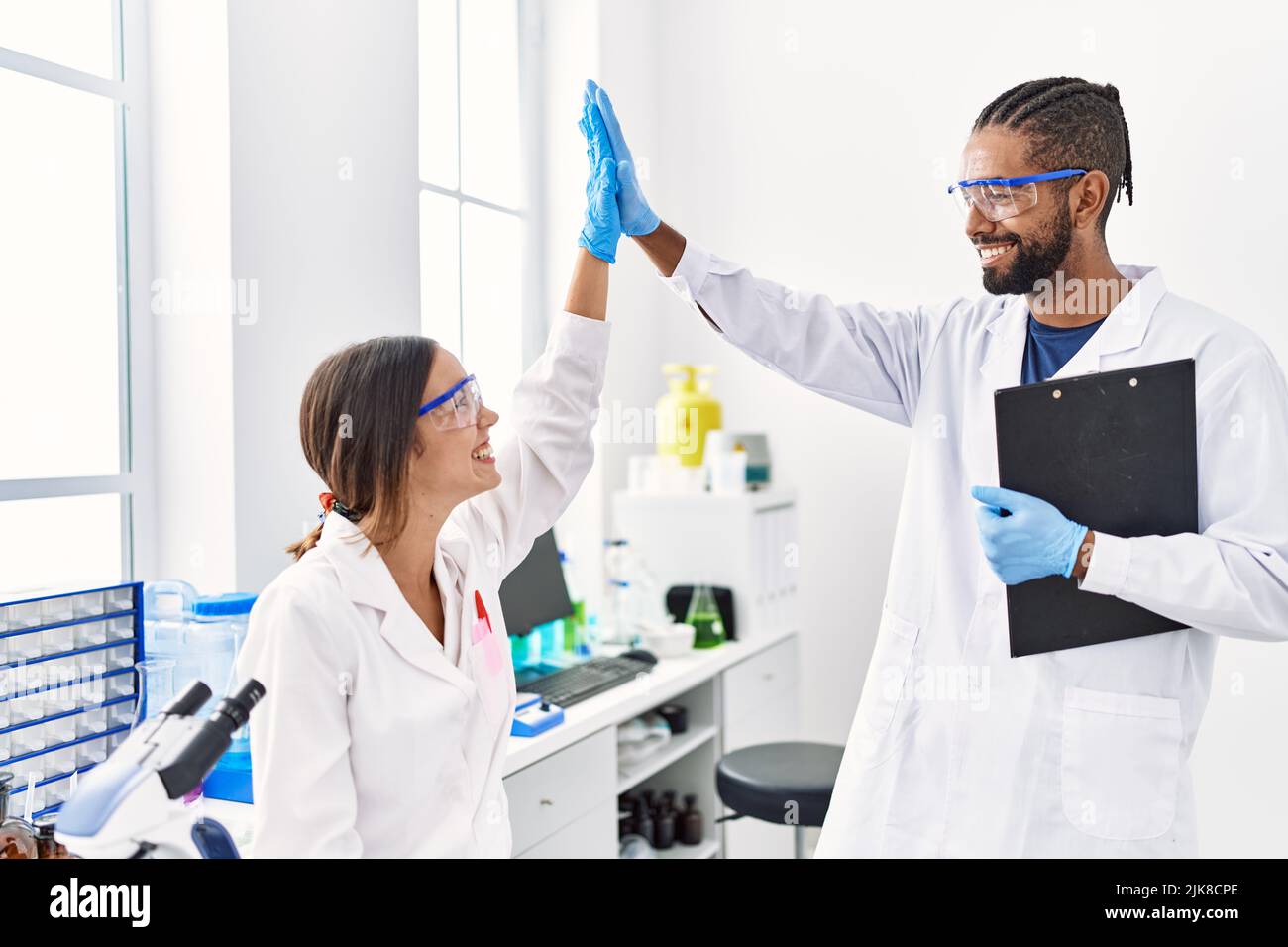 Man and woman scientist partners holding clipboard high five raised up ...