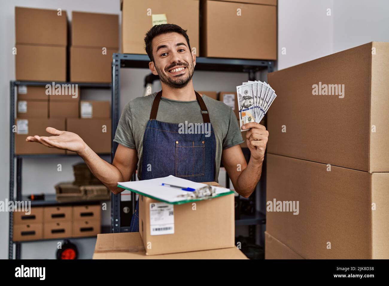 Young hispanic man working at small business ecommerce holding money ...