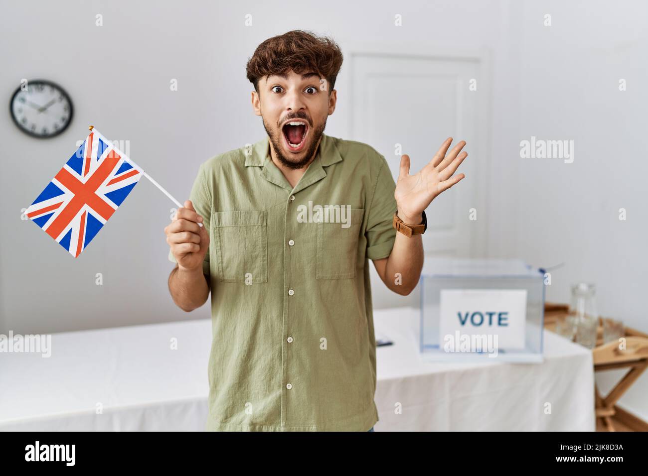 Young arab man at political campaign election holding uk flag ...