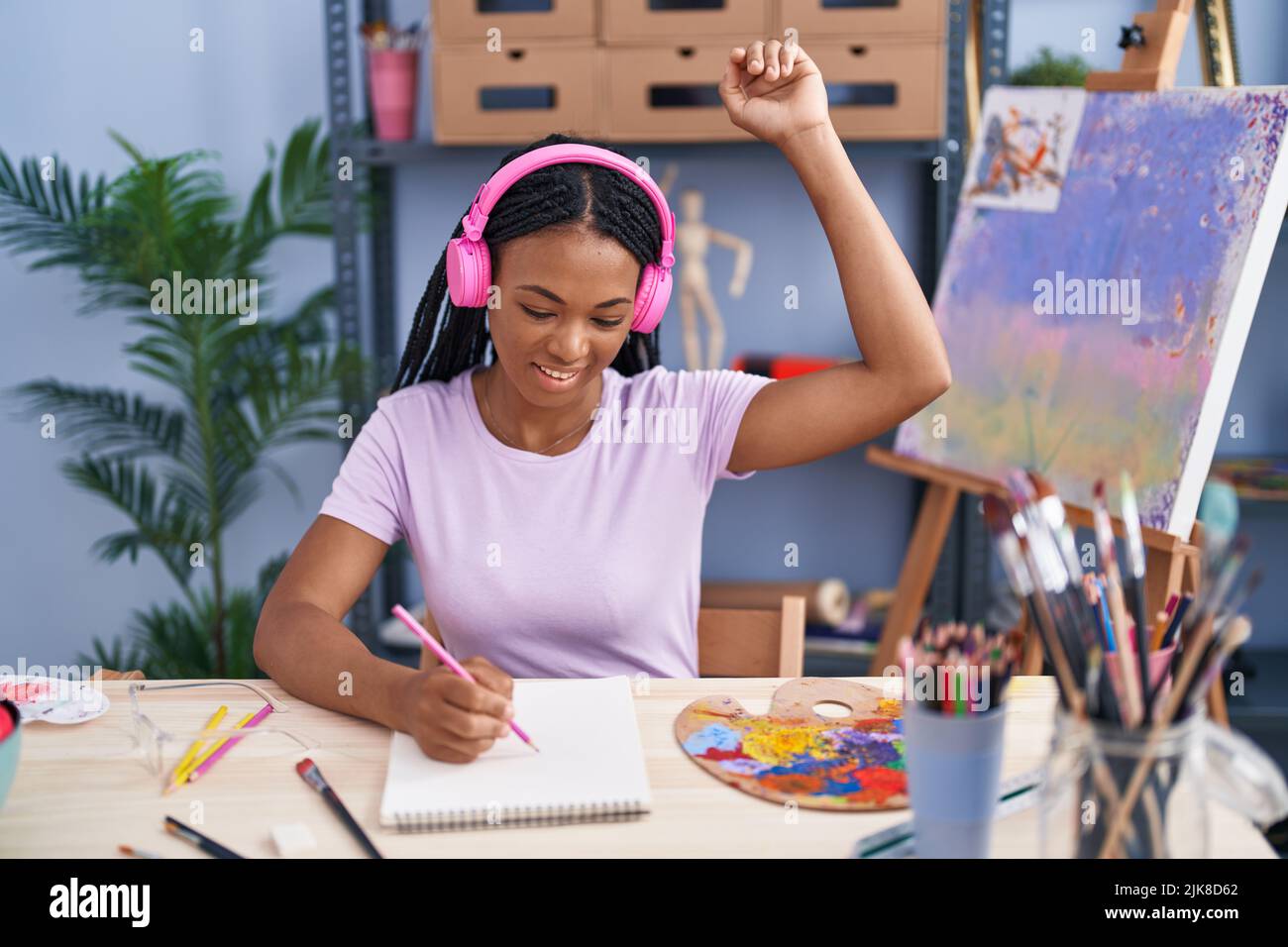 African american woman artist listening to music drawing on notebook at ...
