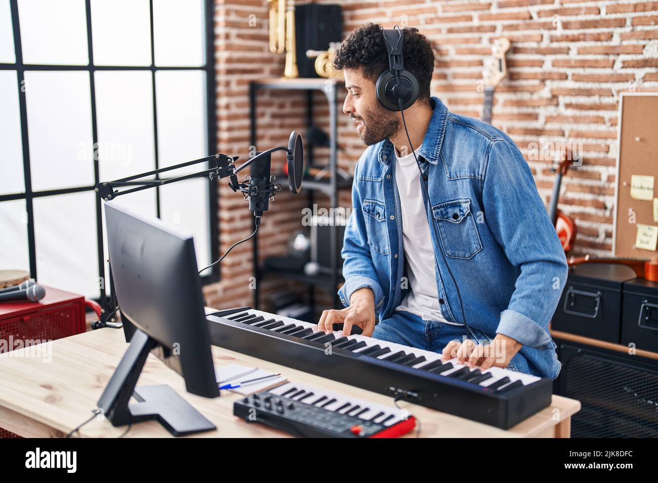Young arab man musician singing song playing piano keyboard at music ...