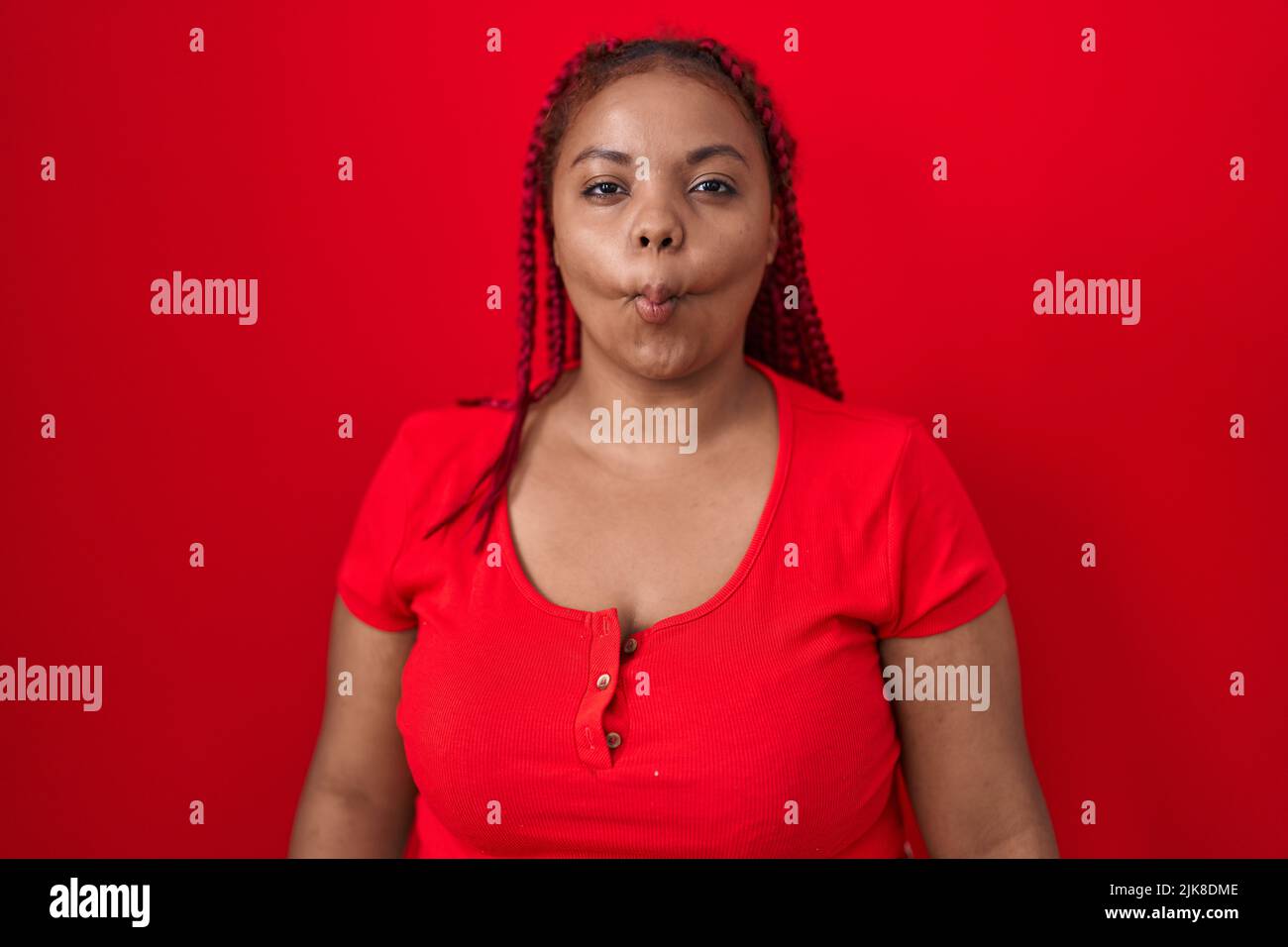 African american woman with braided hair standing over red background ...