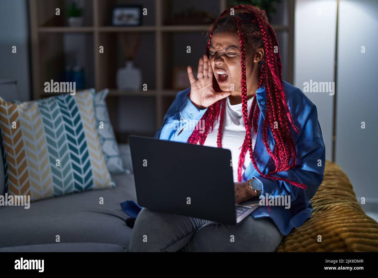 African american woman with braided hair using computer laptop at night ...