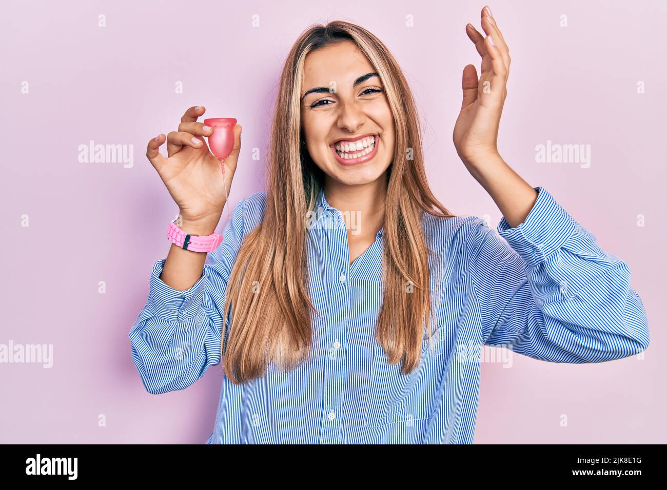 Beautiful hispanic woman holding menstrual cup celebrating victory with ...