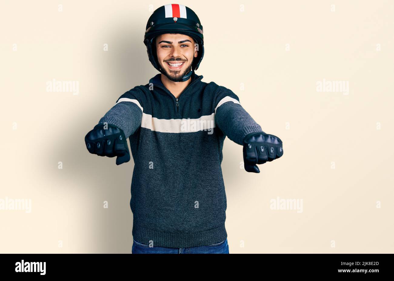 Young hispanic man with beard wearing motorcycle helmet doing driving ...