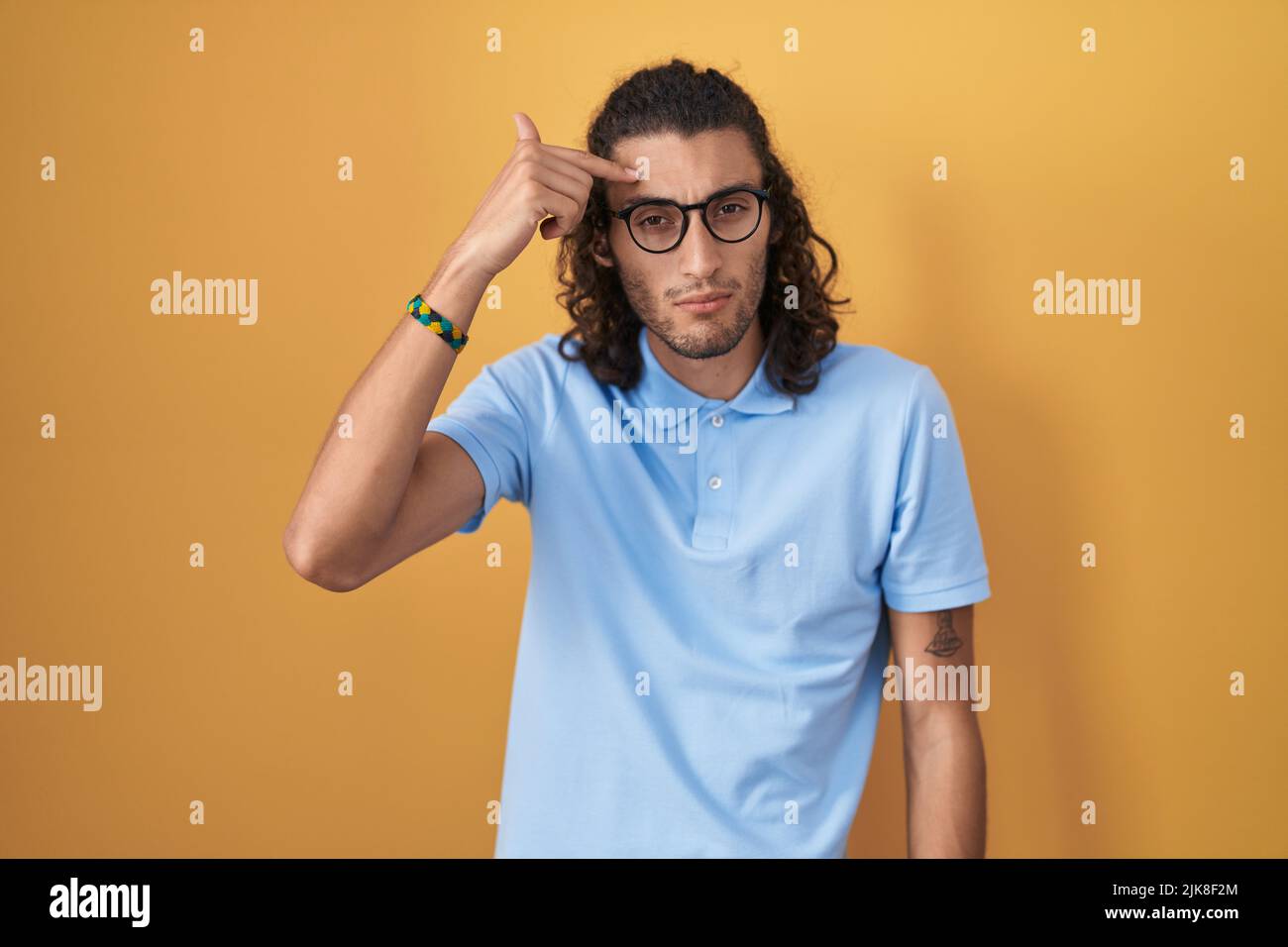 Young hispanic man standing over yellow background pointing unhappy to ...