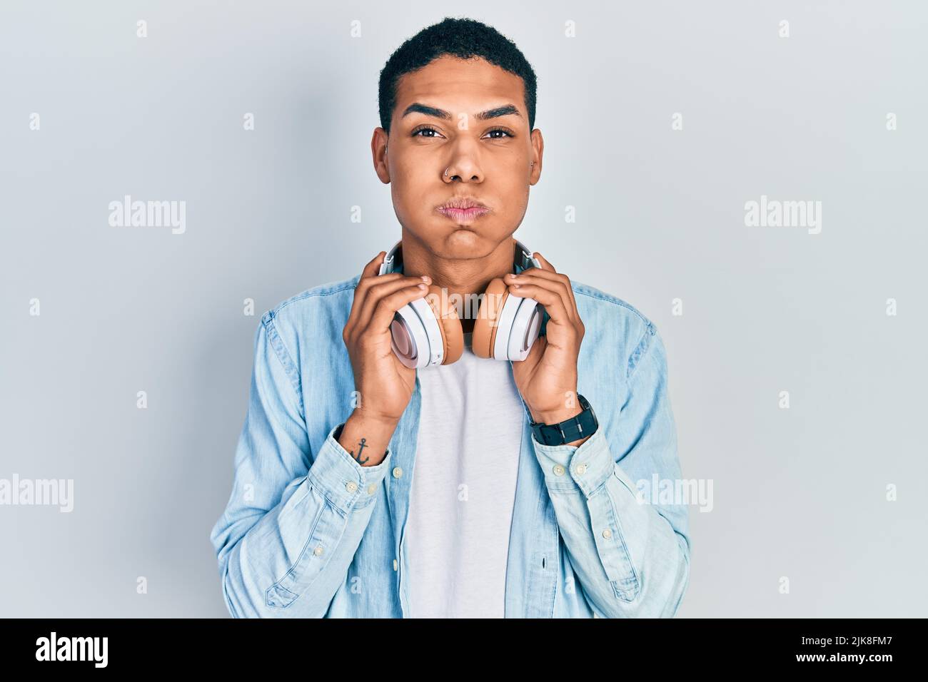 Young african american guy listening to music using headphones puffing ...
