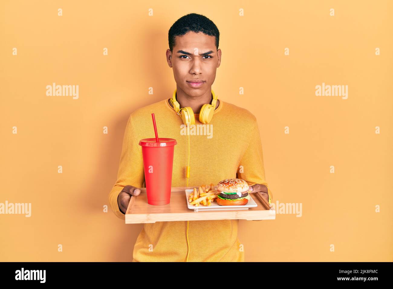 Young african american guy eating a tasty classic burger skeptic and ...