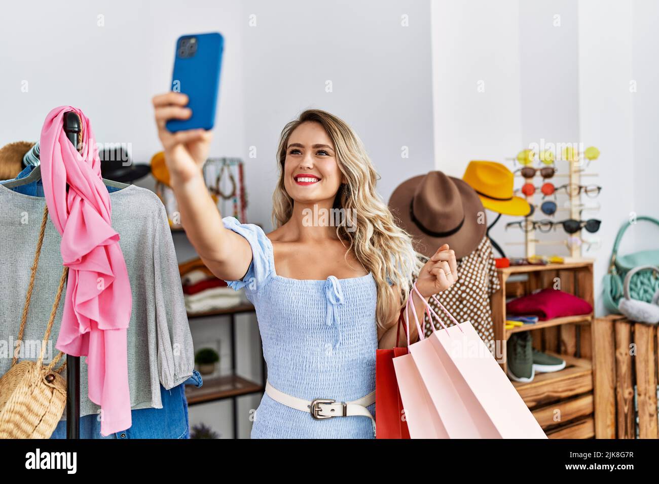 Young woman customer making selfie by smartphone holding shopping bags ...
