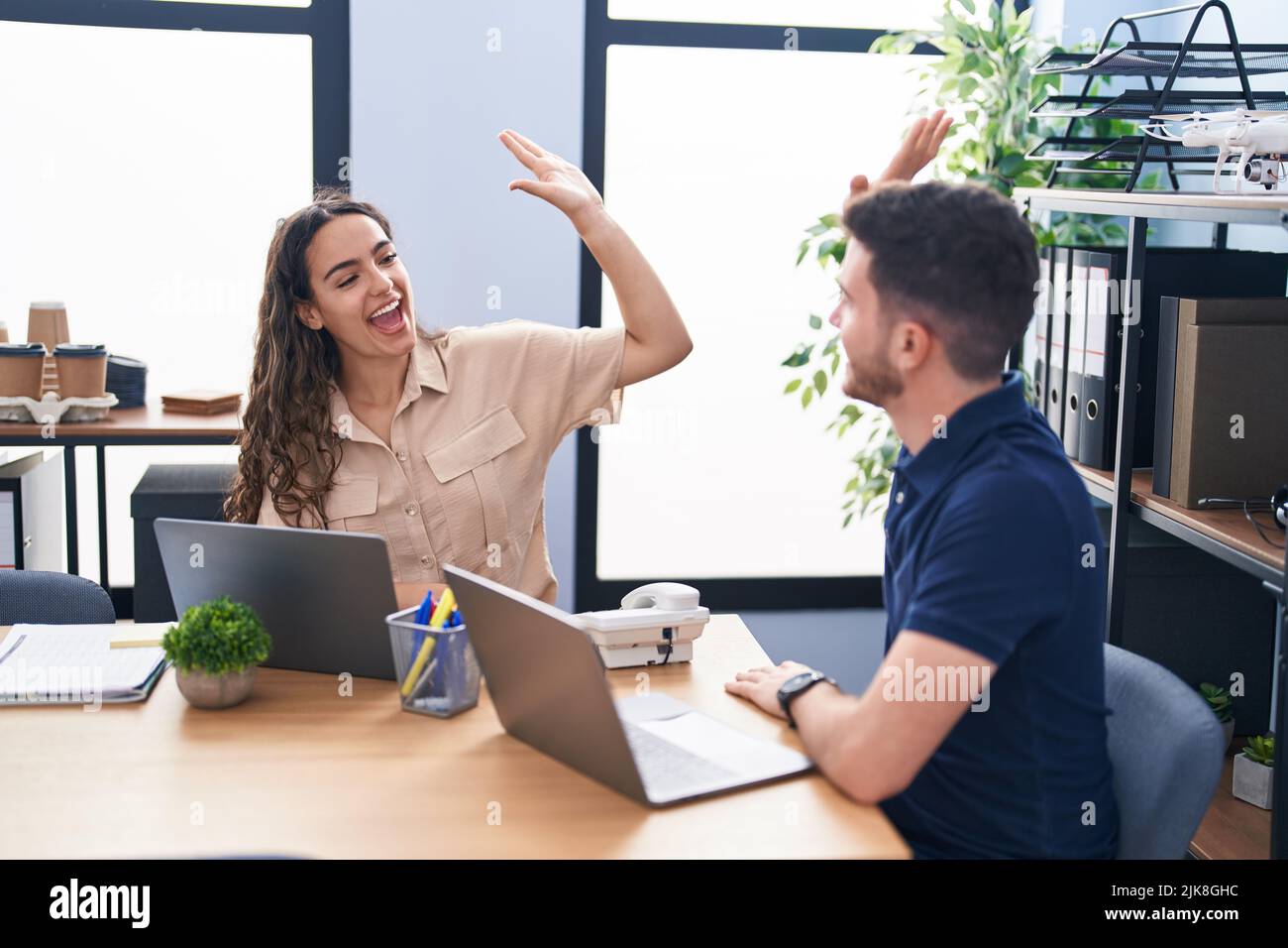 Young hispanic couple business workers high five with hands raised up ...