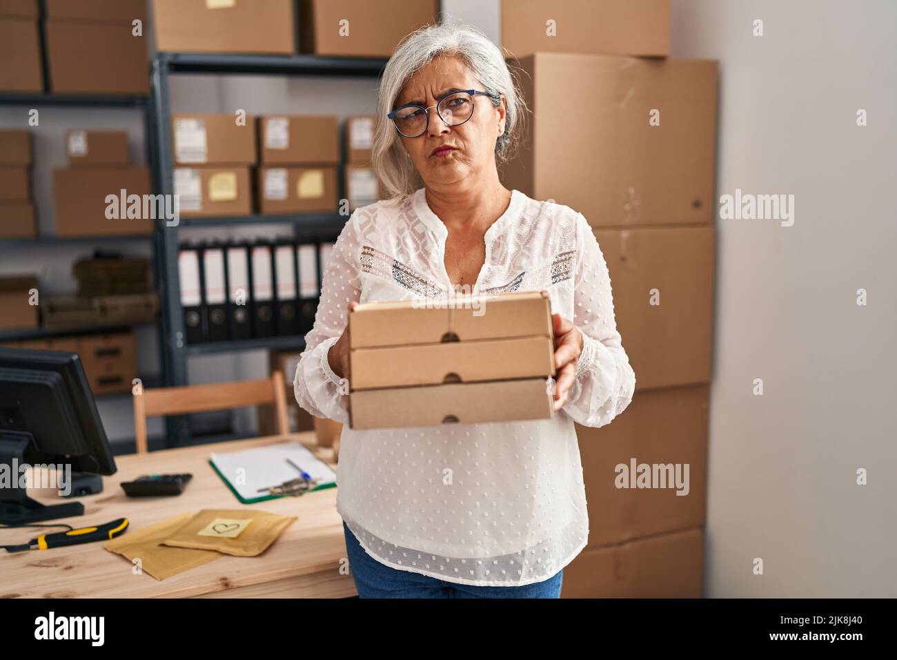 Middle age woman with grey hair working at small business ecommerce ...
