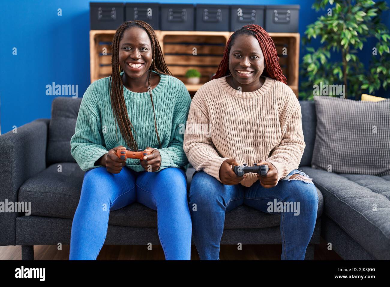 Two african woman playing video game holding controller looking ...
