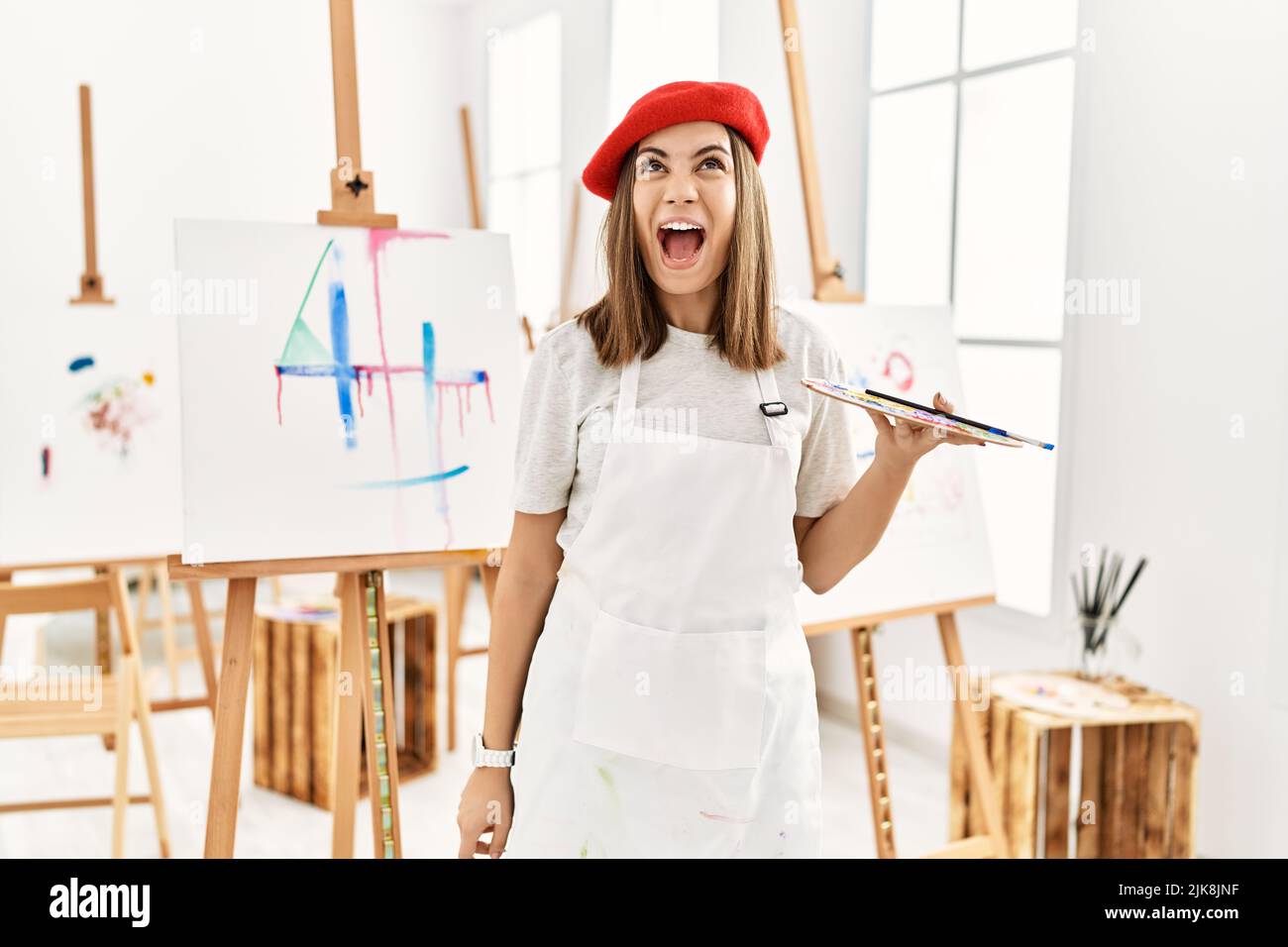 Young artist woman painting on a canvas at art studio angry and mad ...