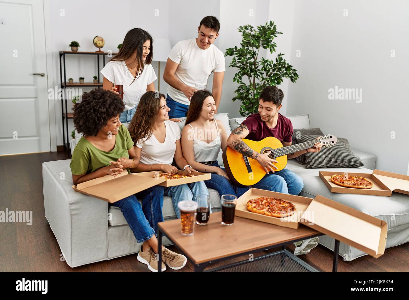 Group of young friends having party eating italian pizza and playing ...