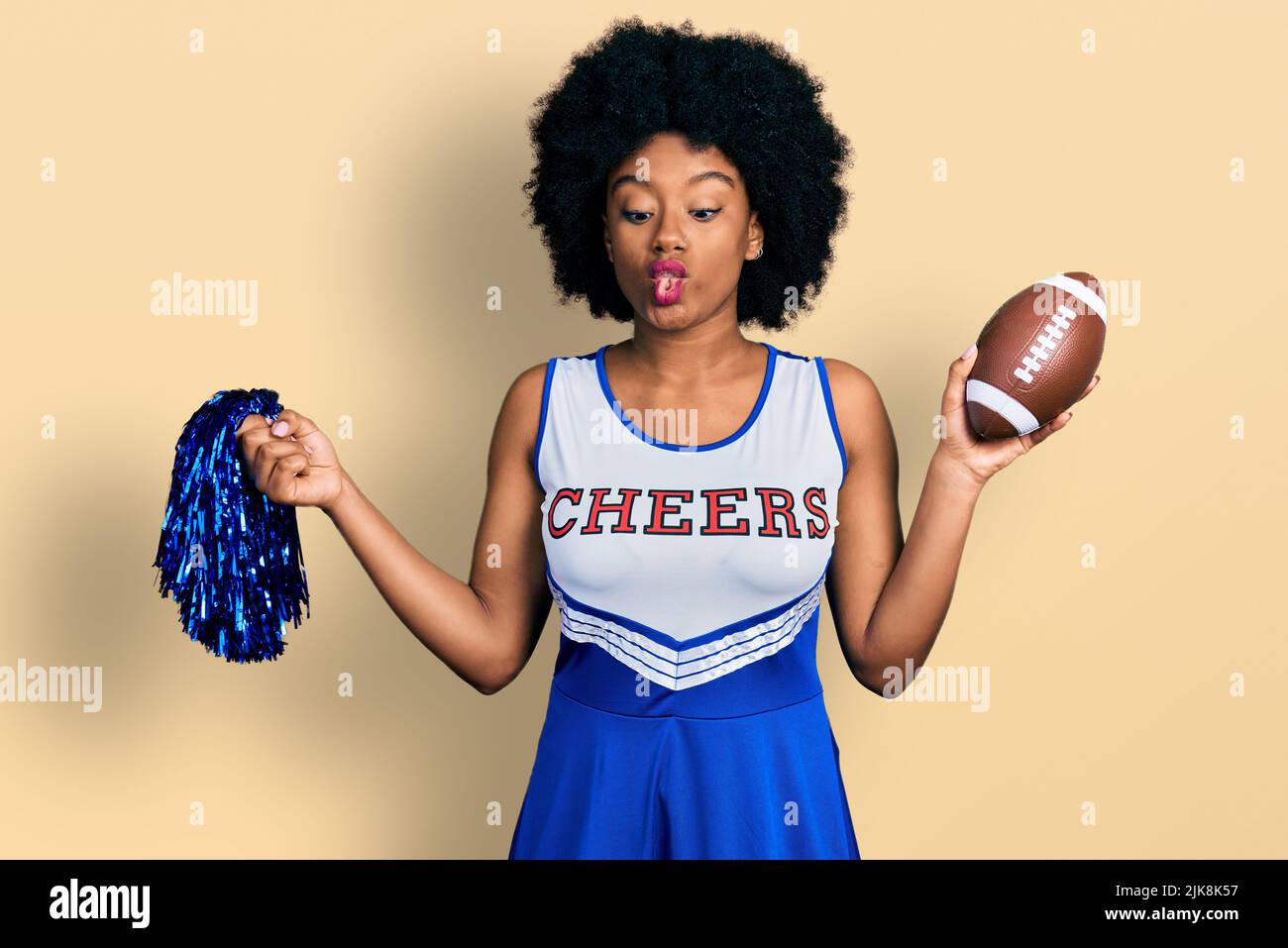 Young african american woman wearing cheerleader uniform holding pompom ...