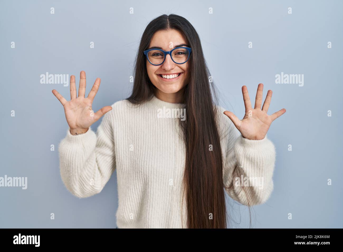 Young hispanic woman wearing casual sweater over blue background ...
