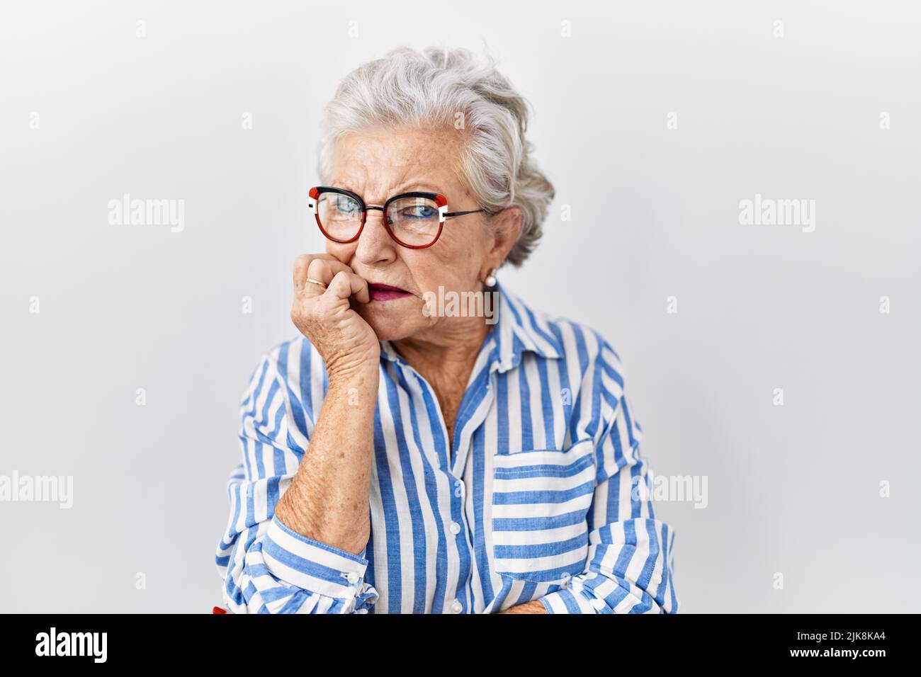Senior woman with grey hair standing over white background looking ...